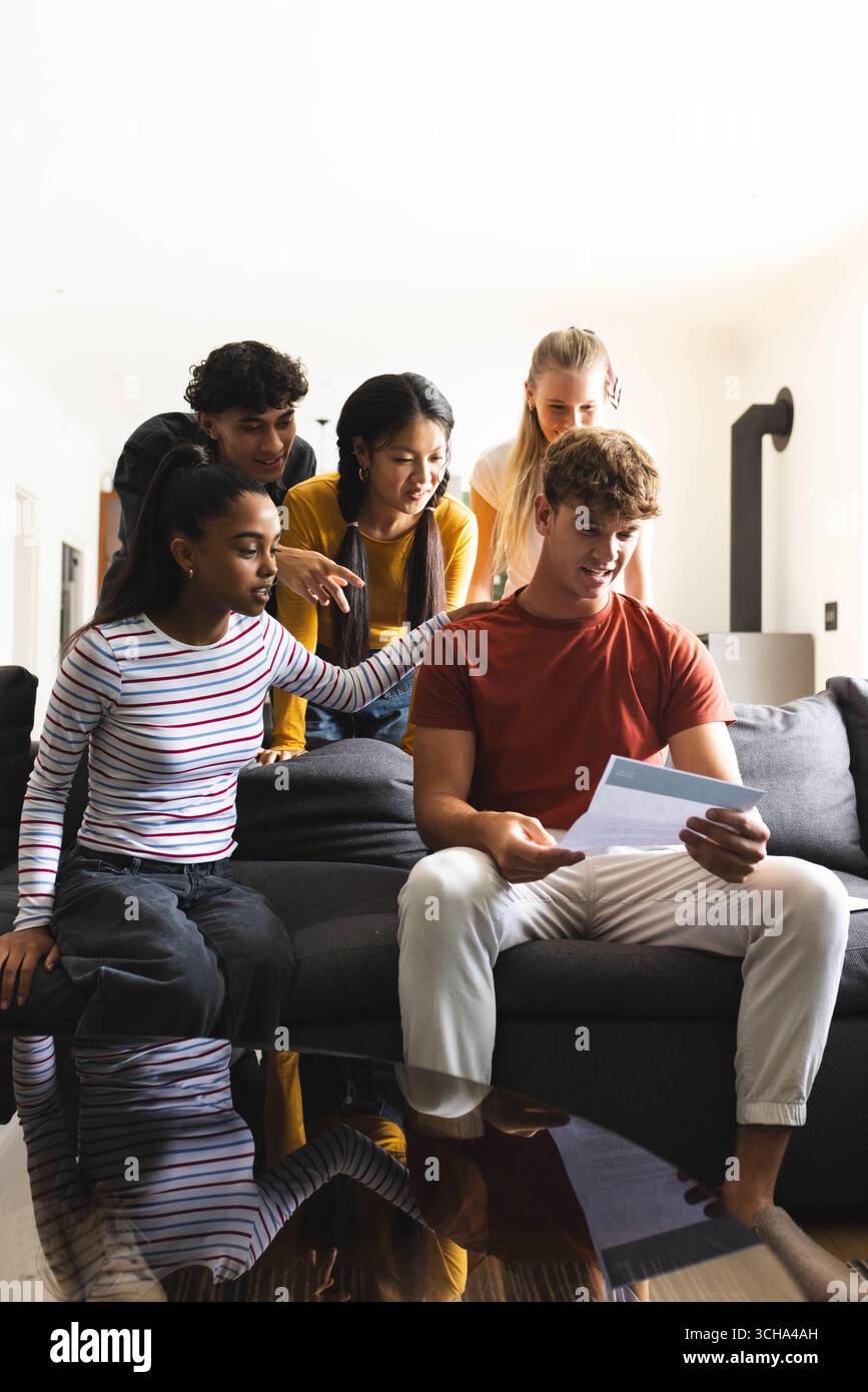 Diverse teenagers celebrating exam results together at home, smiling ...