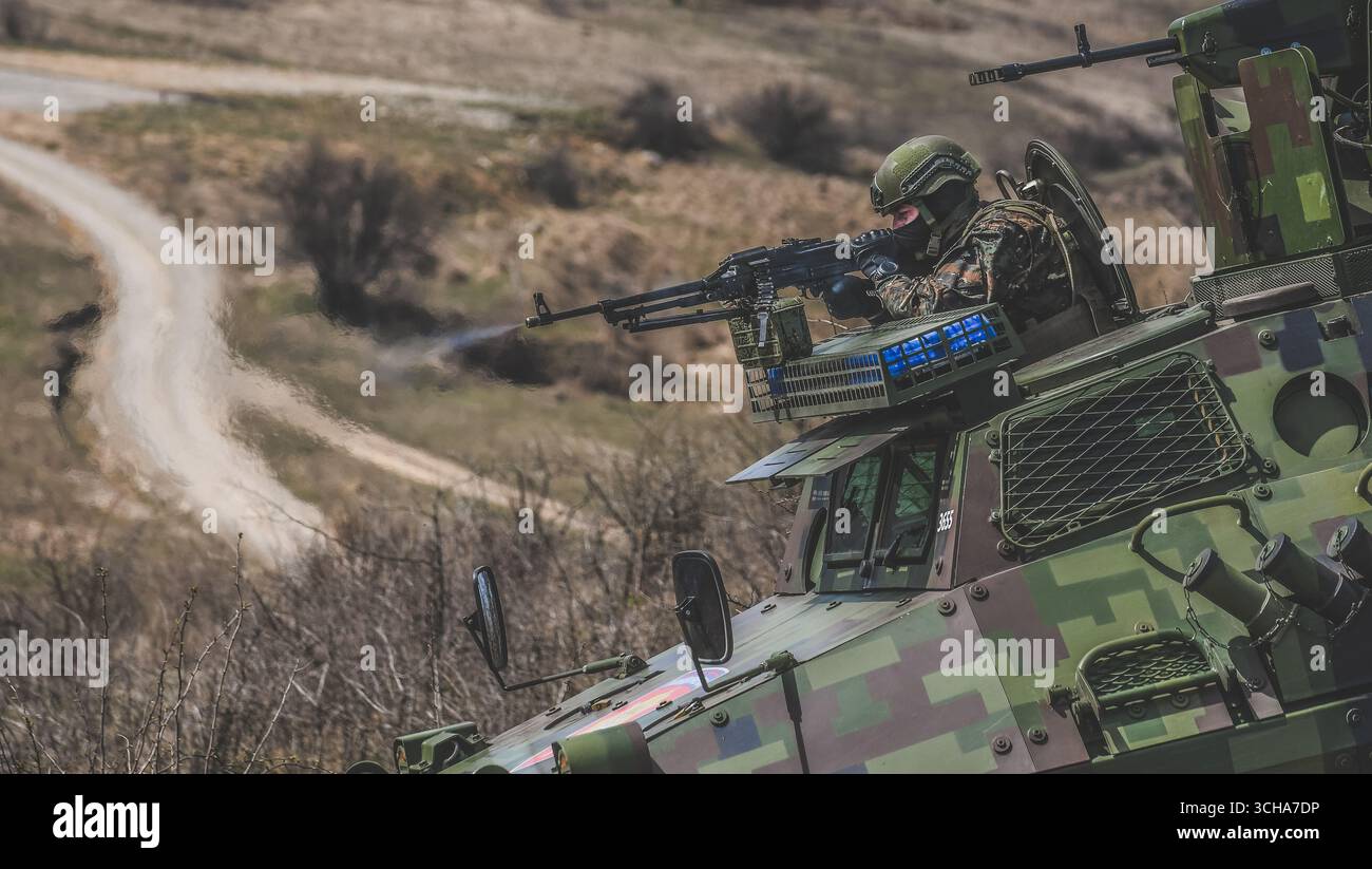 Soldier firing a machine gun from the roof of a special armored vehicle ...