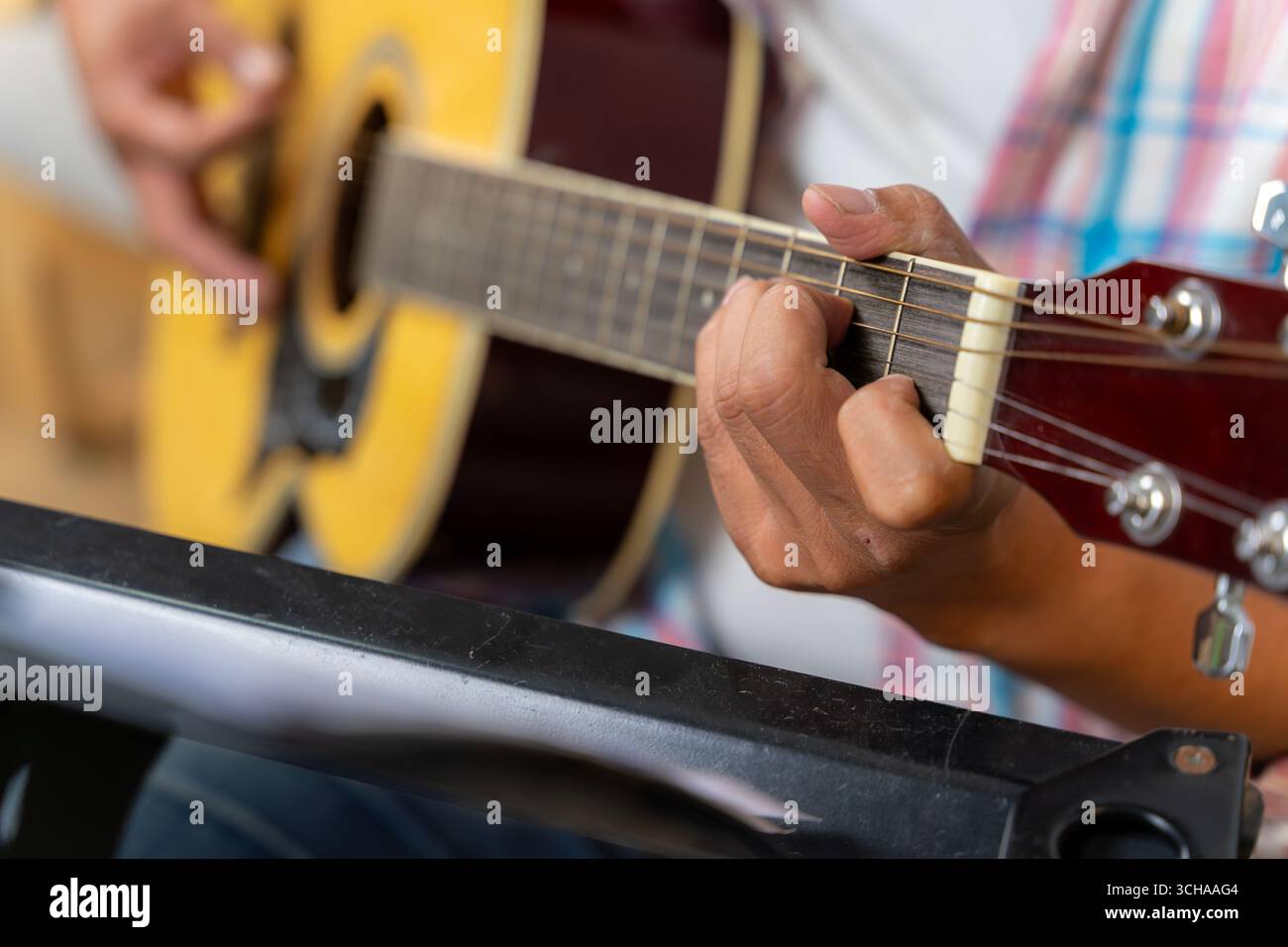 A close-up view of a hand pressing chords on an acoustic guitar ...