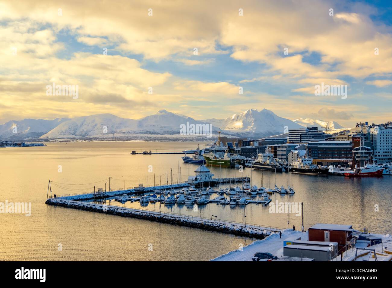 Snow-covered Troms harbor with docked boats and ships, nestled against ...