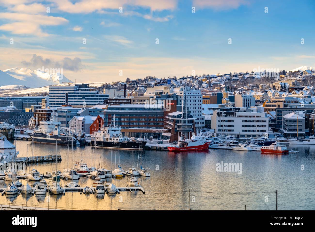 Snow-covered Troms harbor with docked boats and ships, nestled against ...