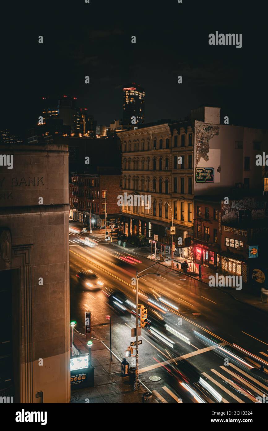Night traffic streaks along a historic New York street lined with older ...
