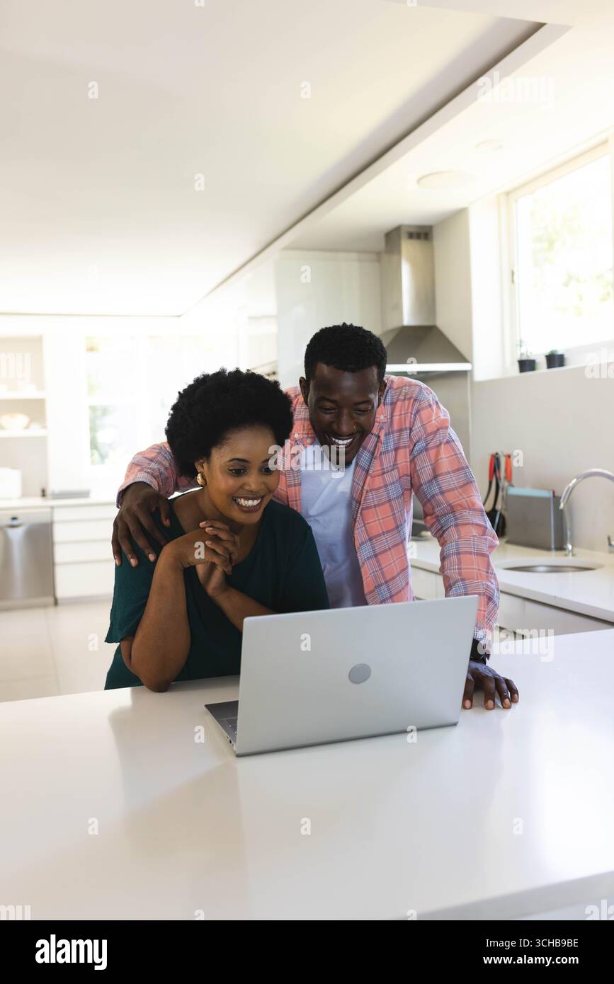 Standing African American couple leaning over kitchen island in modern ...