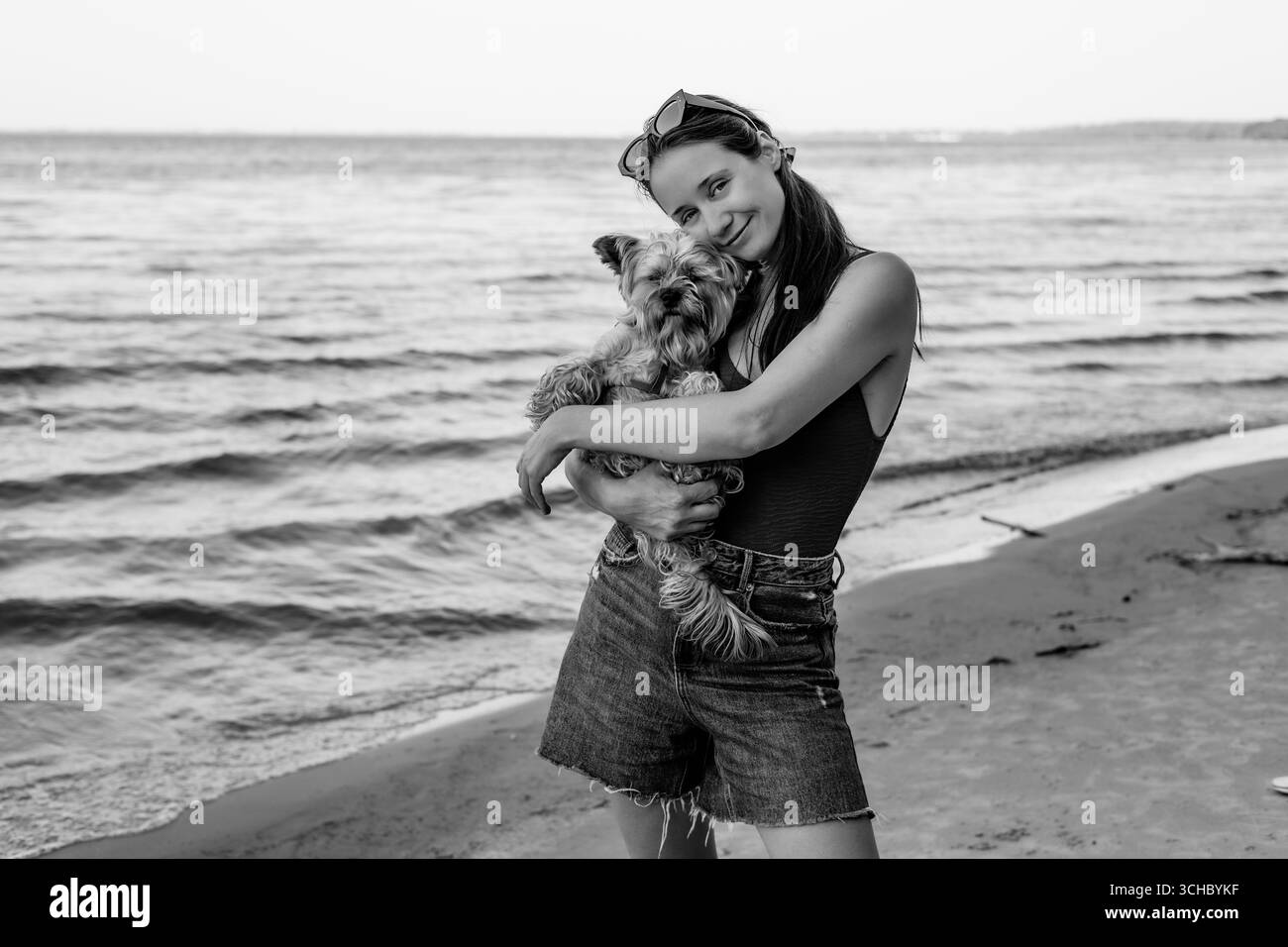 Tender portrait of young woman hugging and kissing small Yorkshire ...