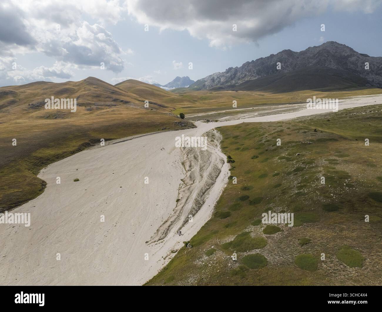Aerial view of a stark, sandy riverbed carving through the golden ...