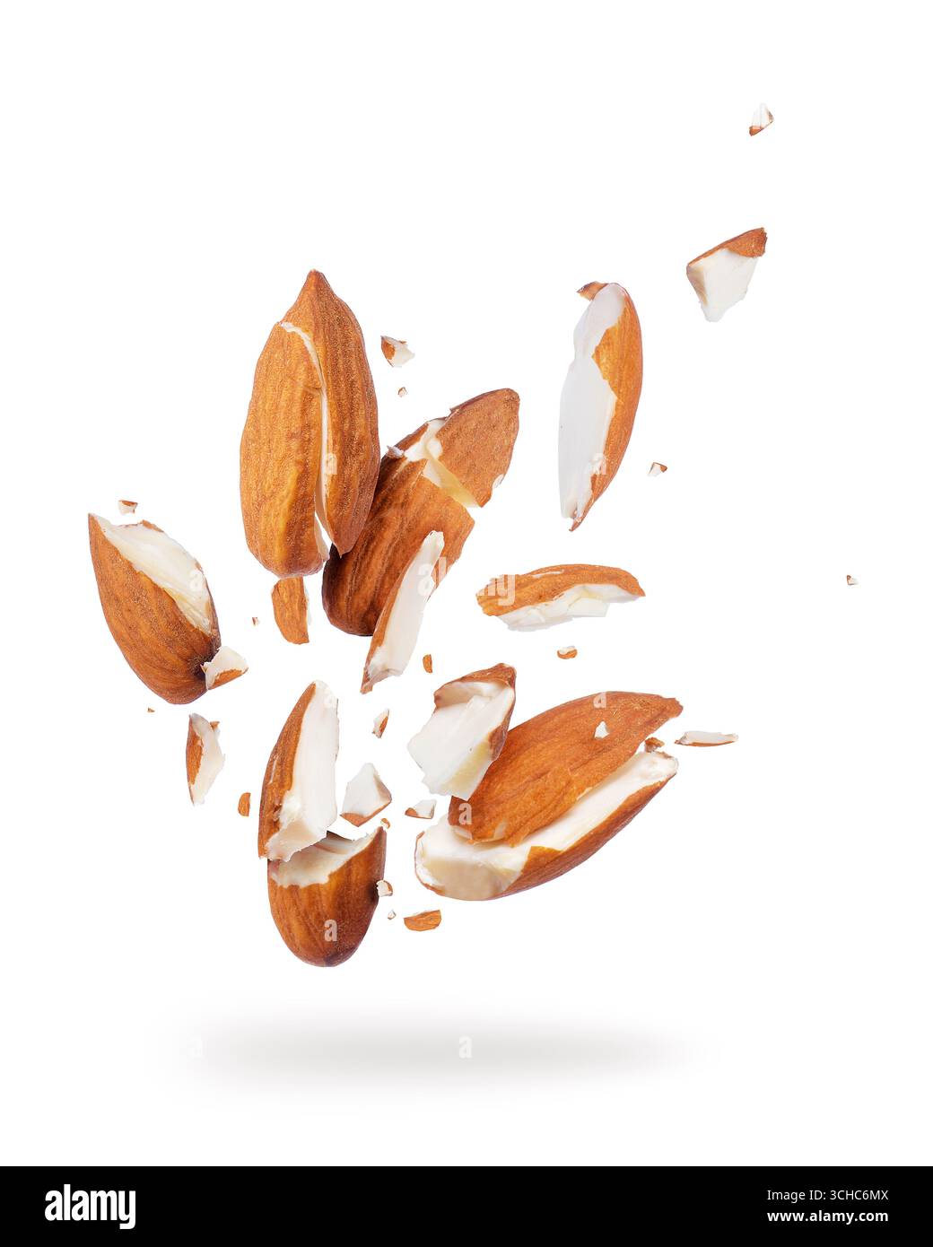 Almonds crushed into pieces, frozen in the air close-up on a white ...