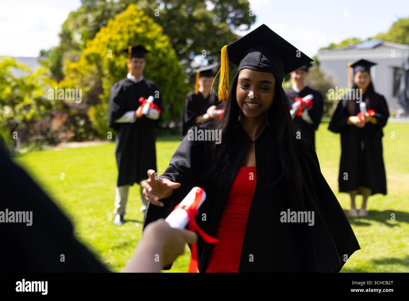 Graduating students in caps and gowns celebrating with diplomas ...