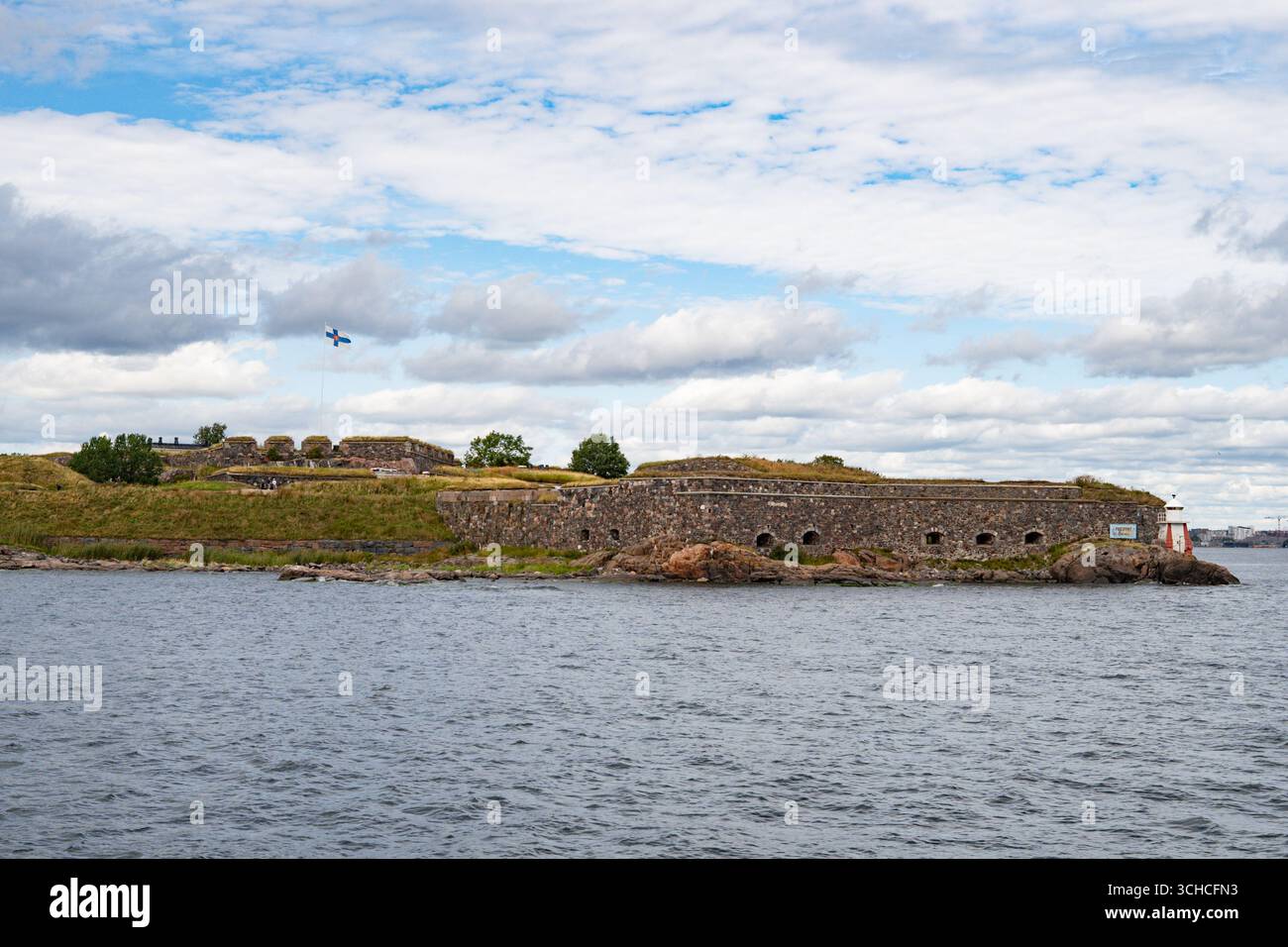 Historic fortress island with stone walls and Finnish flag under cloudy ...