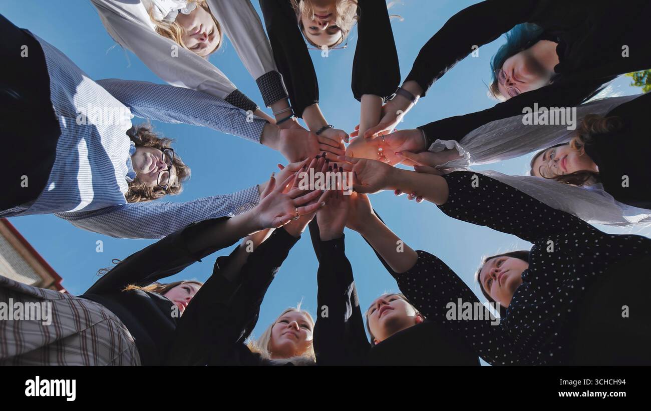 Students joining hands together in a circle, symbolizing unity and ...