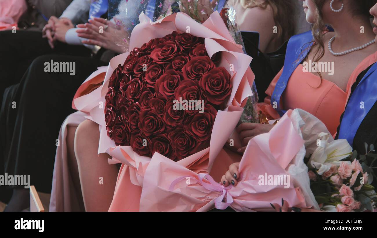 Graduate student holding large red rose bouquet, commemorating academic ...