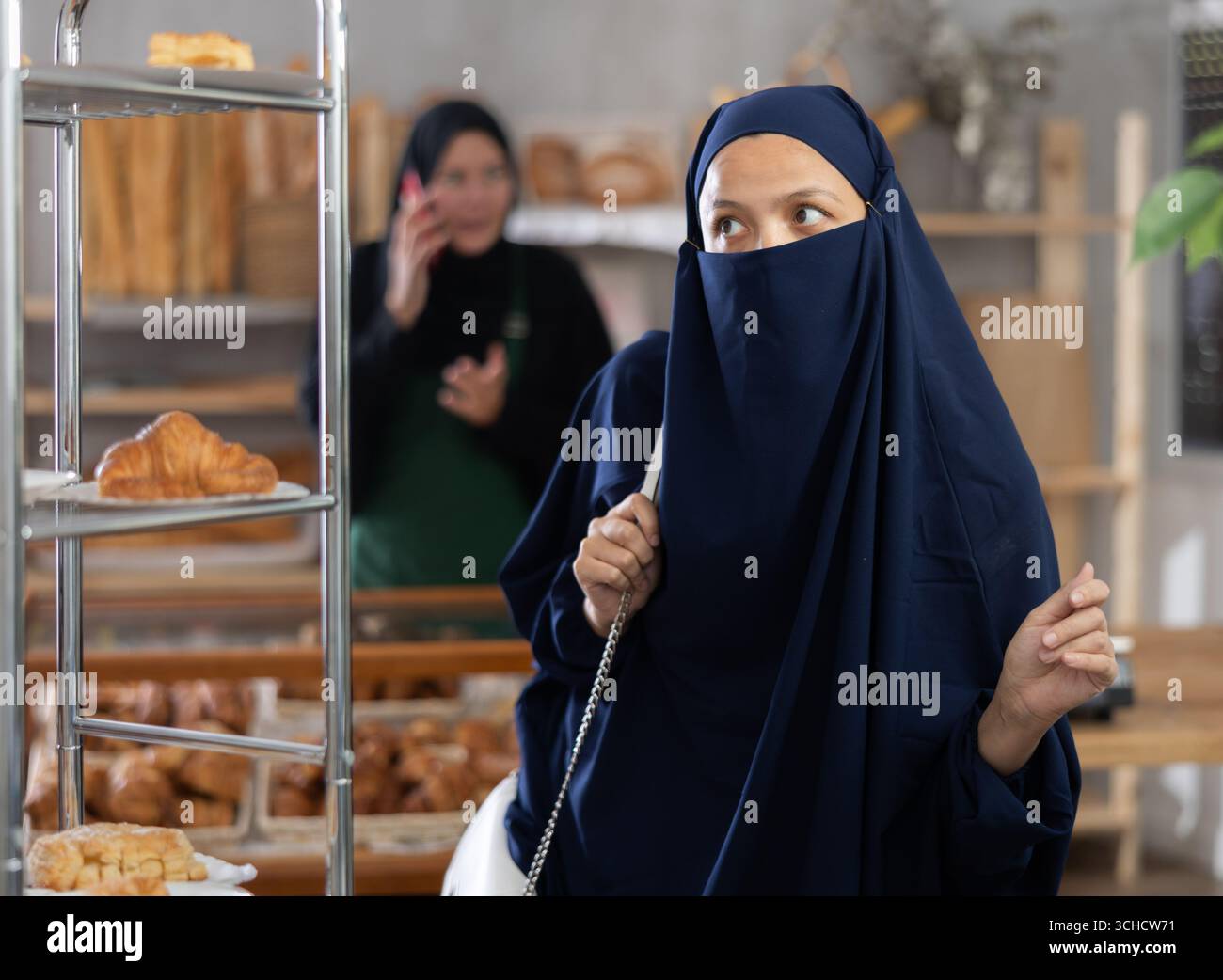 Female customer in muslim clothing and niqab chooses bread and other ...