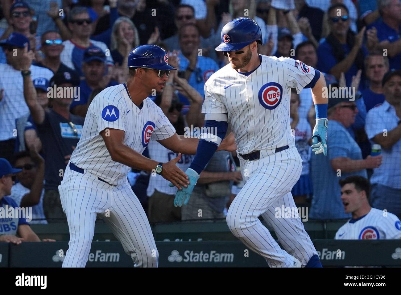 Chicago Cubs' Ian Happ, right, celebrates with third base coach Quintin ...
