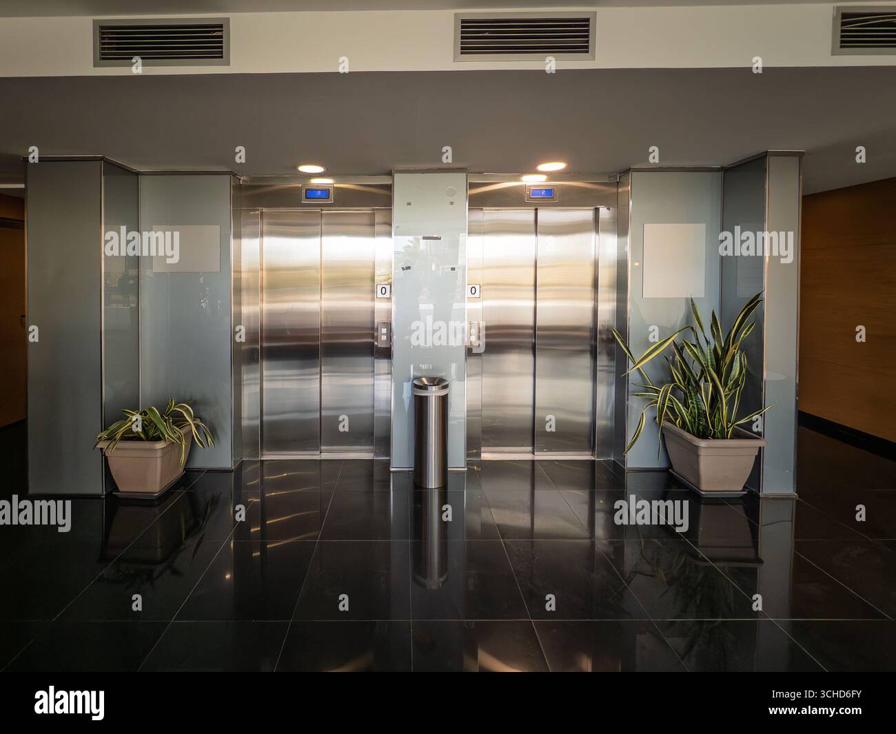 Two steel lift doors in a modern office lobby, with floor indicators ...
