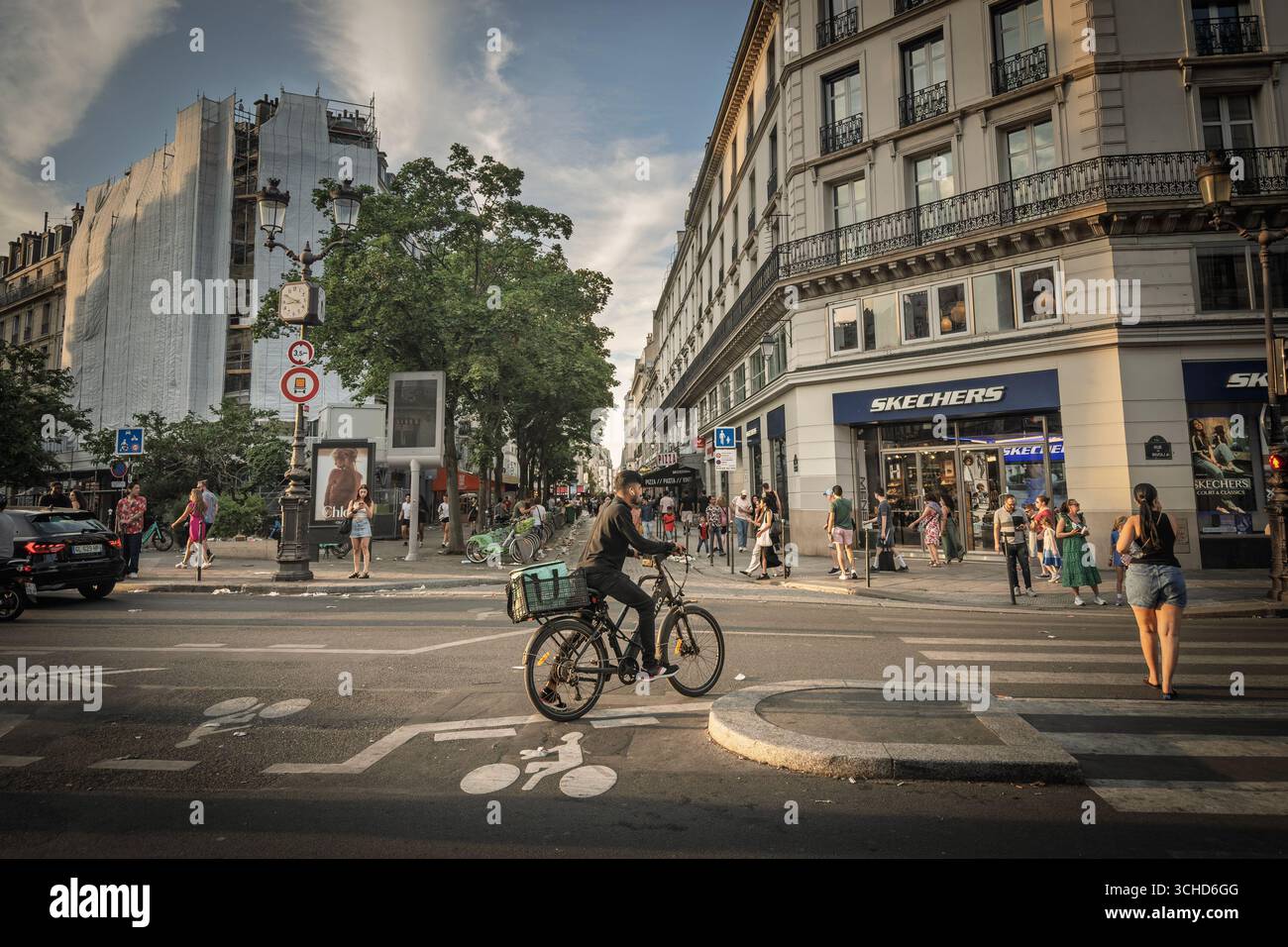 PARIS, FRANCE - JUNE 22, 2025: A food delivery man rides a bicycle on a ...