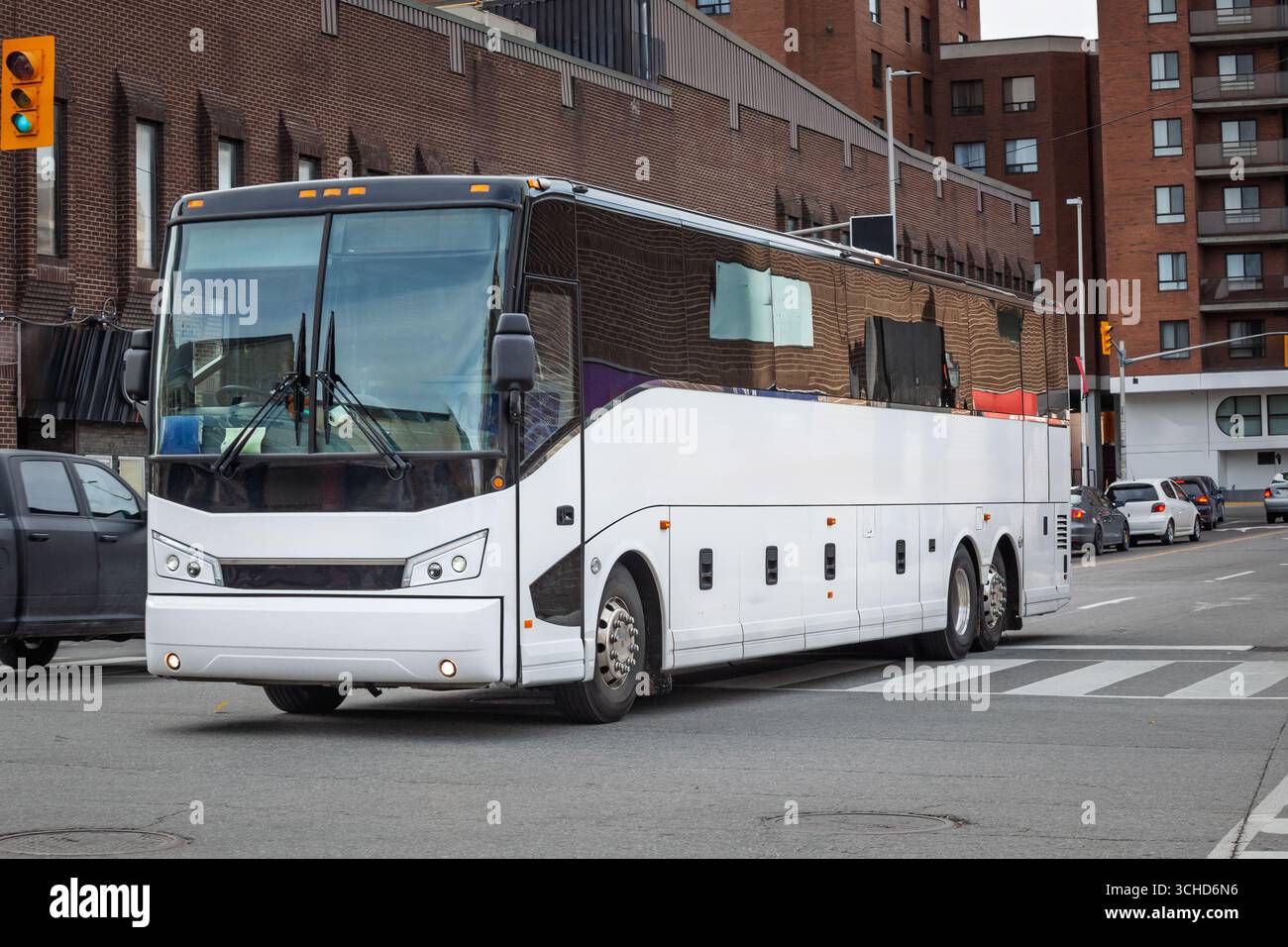A large intercity motorcoach turns through an urban intersection in an ...