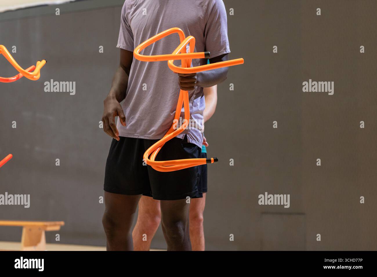 Diverse male training partners gripping bright orange agility poles ...