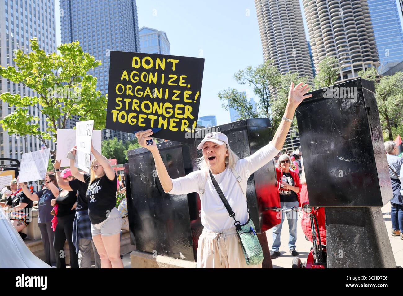 People hold signs and wave at honking cars driving by at the DINE ...