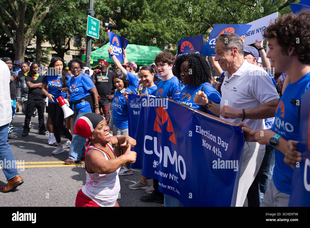 A group of people in blue shirts hold a banner with "CUOMO" on it ...