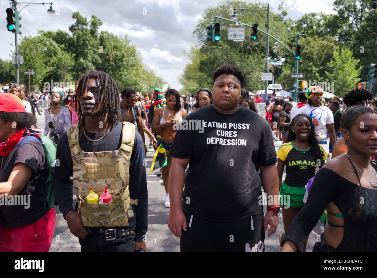 A diverse group of people walk down a street. The main focus is on two ...