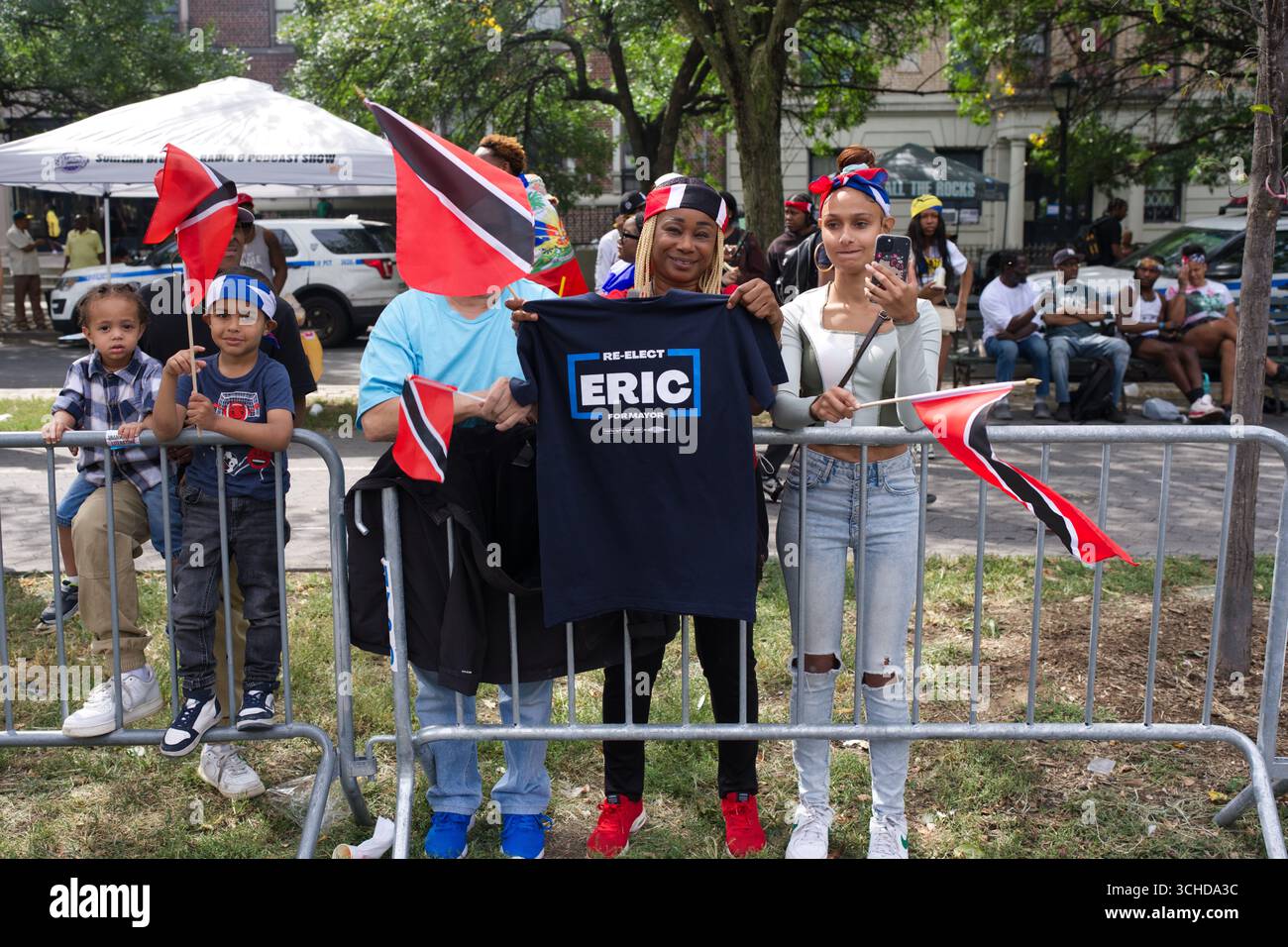 A group of people, including children, hold Trinidad and Tobago flags ...