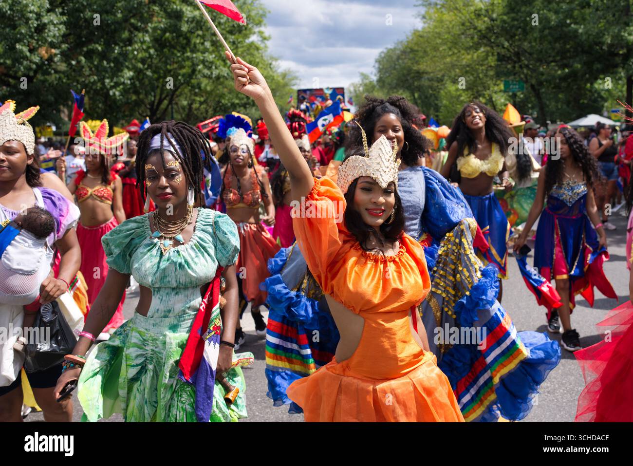 A group of women in colorful, festive attire participate in an outdoor ...