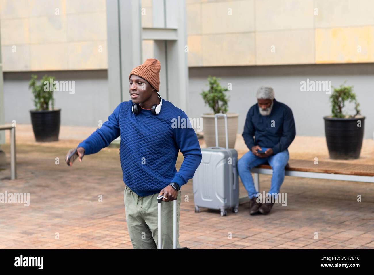 African american male travelers pulling suitcases across plaza while ...