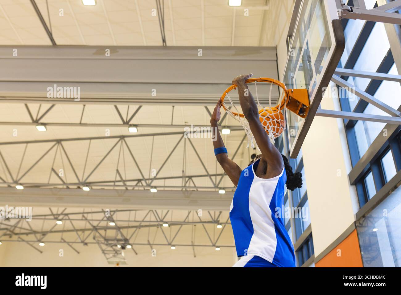 Male in uniform leaping dunking basketball at hoop on court, copy space ...