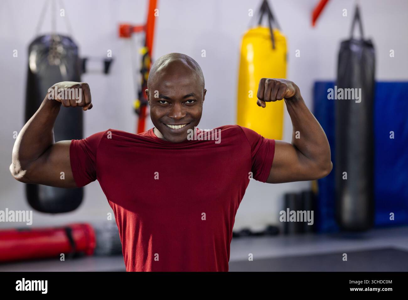 African american man flexing biceps, smiling in boxing gym with black ...