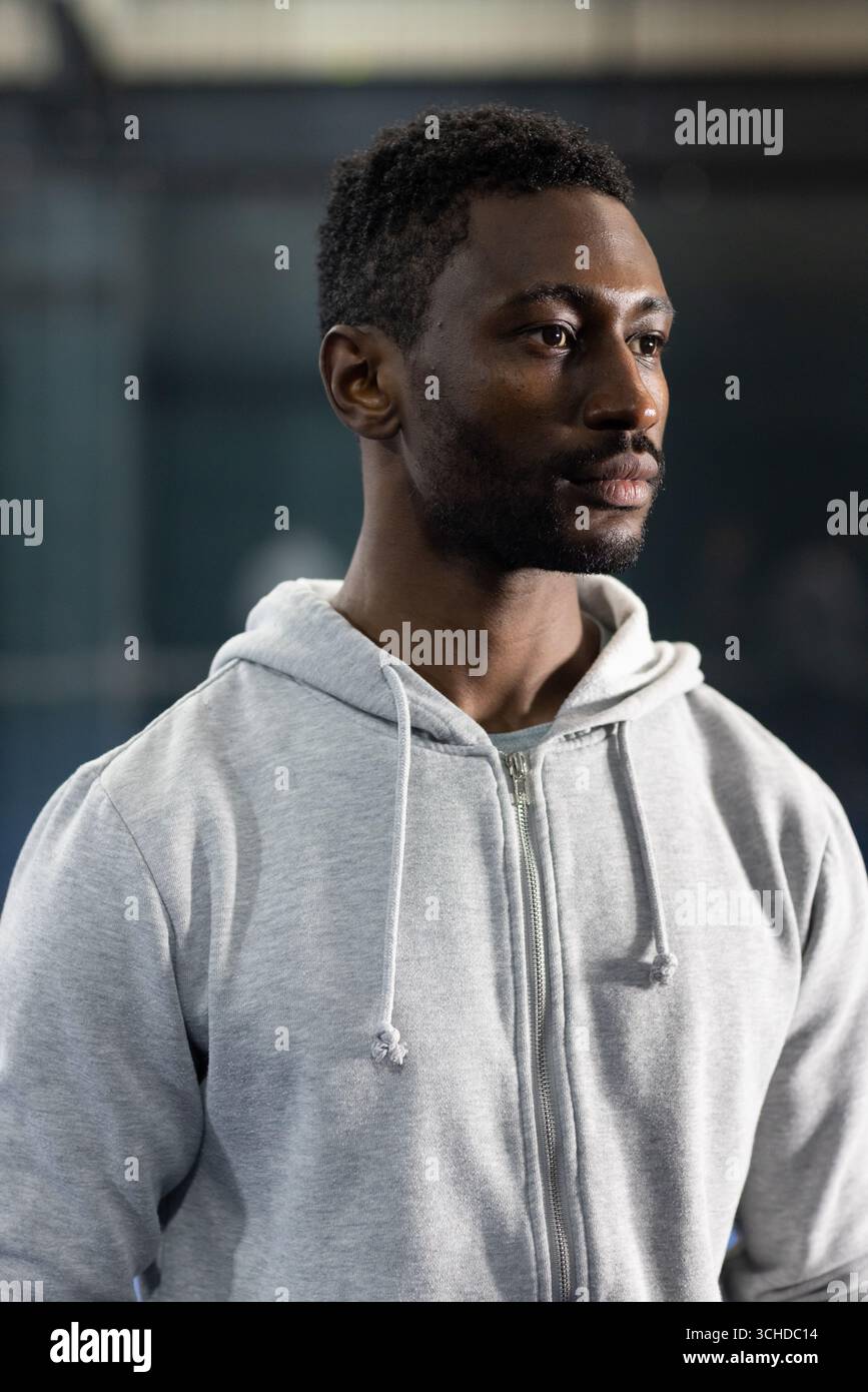 African american man standing in large training facility in grey zip-up ...