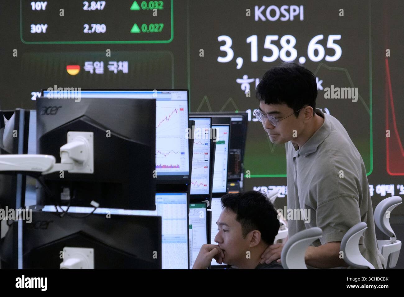 Currency traders watch monitors near a screen showing the Korea ...