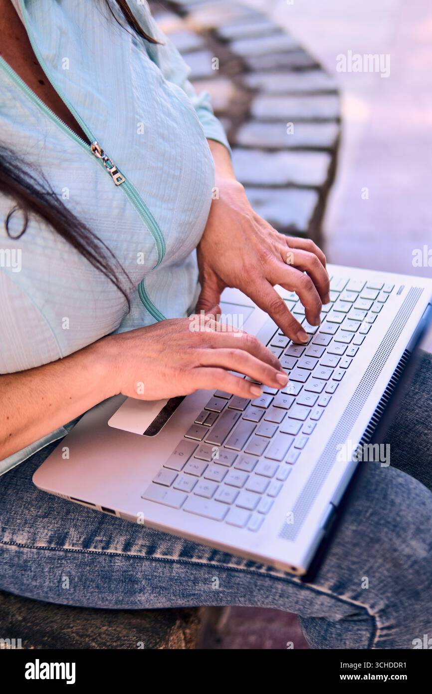 View of the hands of an adult professional woman typing on a laptop ...