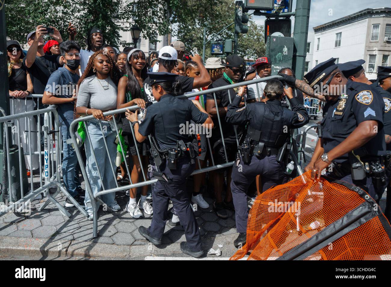 NYPD officers prevent a crowd of parade goers from crossing the street ...
