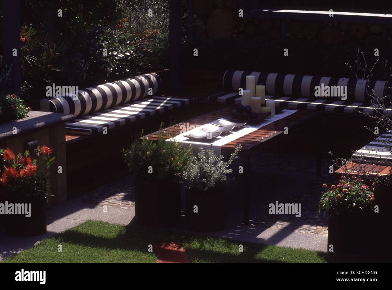 Stylish seating area features striped cushions and potted plants ...
