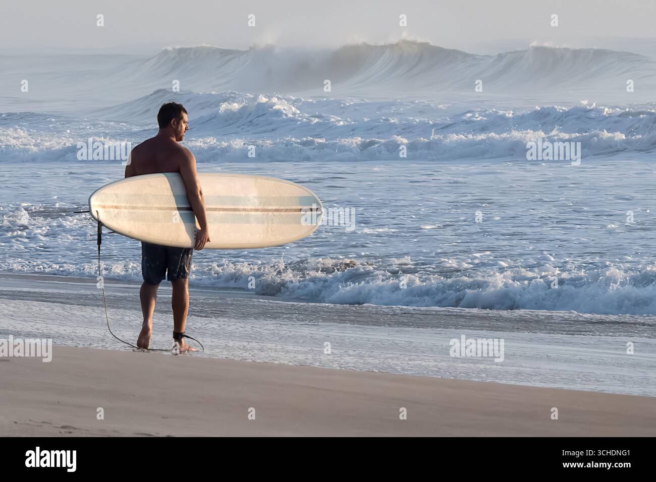 Surfer entering the surf at sunrise in Fernandina Beach on Amelia ...