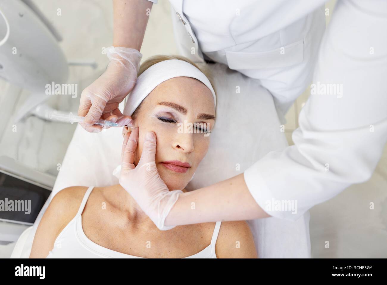 Senior woman receiving aesthetic facial injection by professional ...