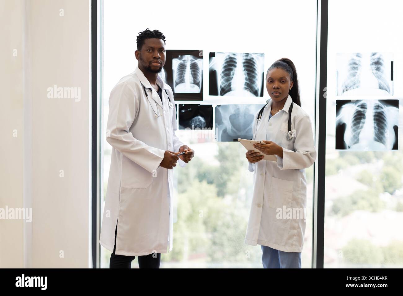 Male and female doctors reviewing x-rays near window in clinical ...