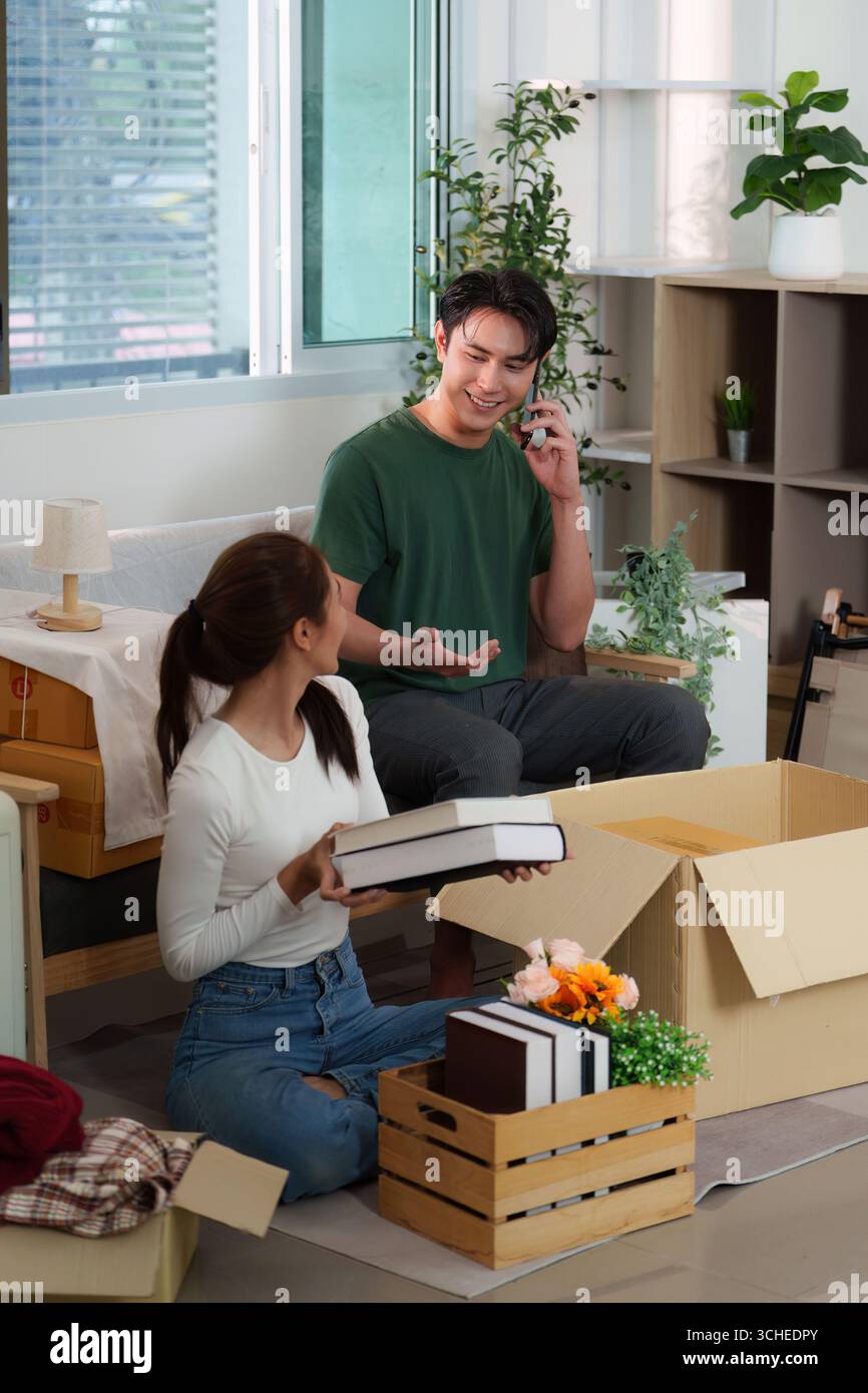 Home Setup. Young couple discussing while unpacking boxes in their new ...