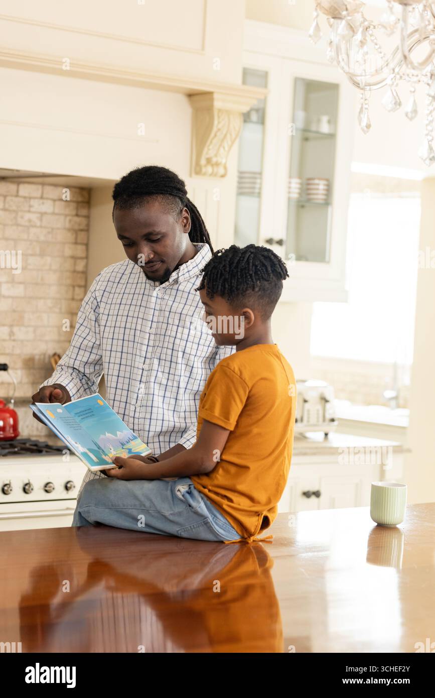 African American father reading storybook to son in cozy kitchen ...
