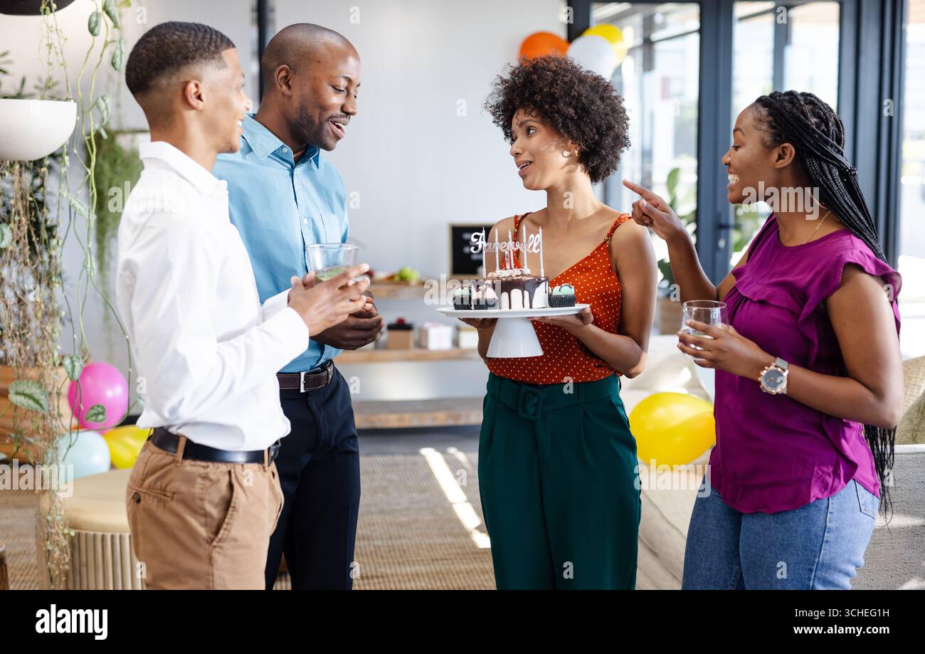 Diverse colleagues celebrating birthday with cake and drinks in modern ...