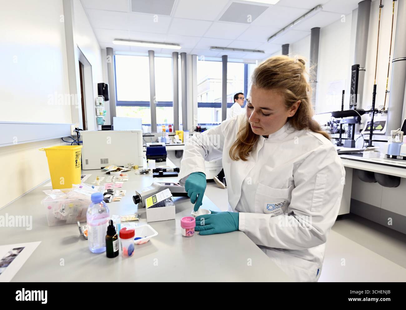 A laboratory technician performs drug analyses during a press briefing ...