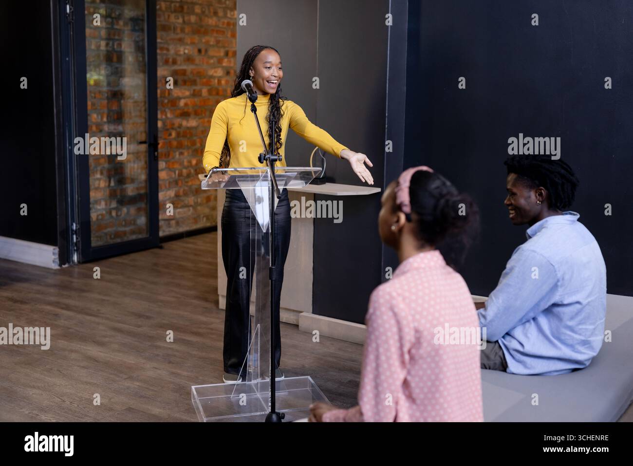 Woman presenting at podium engaging audience in modern office setting ...
