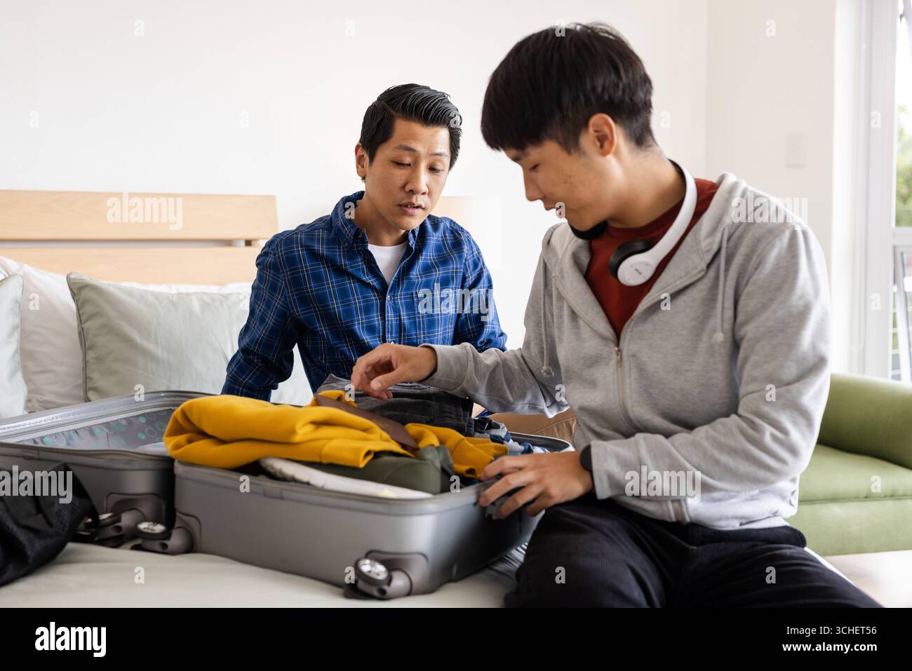 Asian father and son packing suitcase together at home, preparing for ...