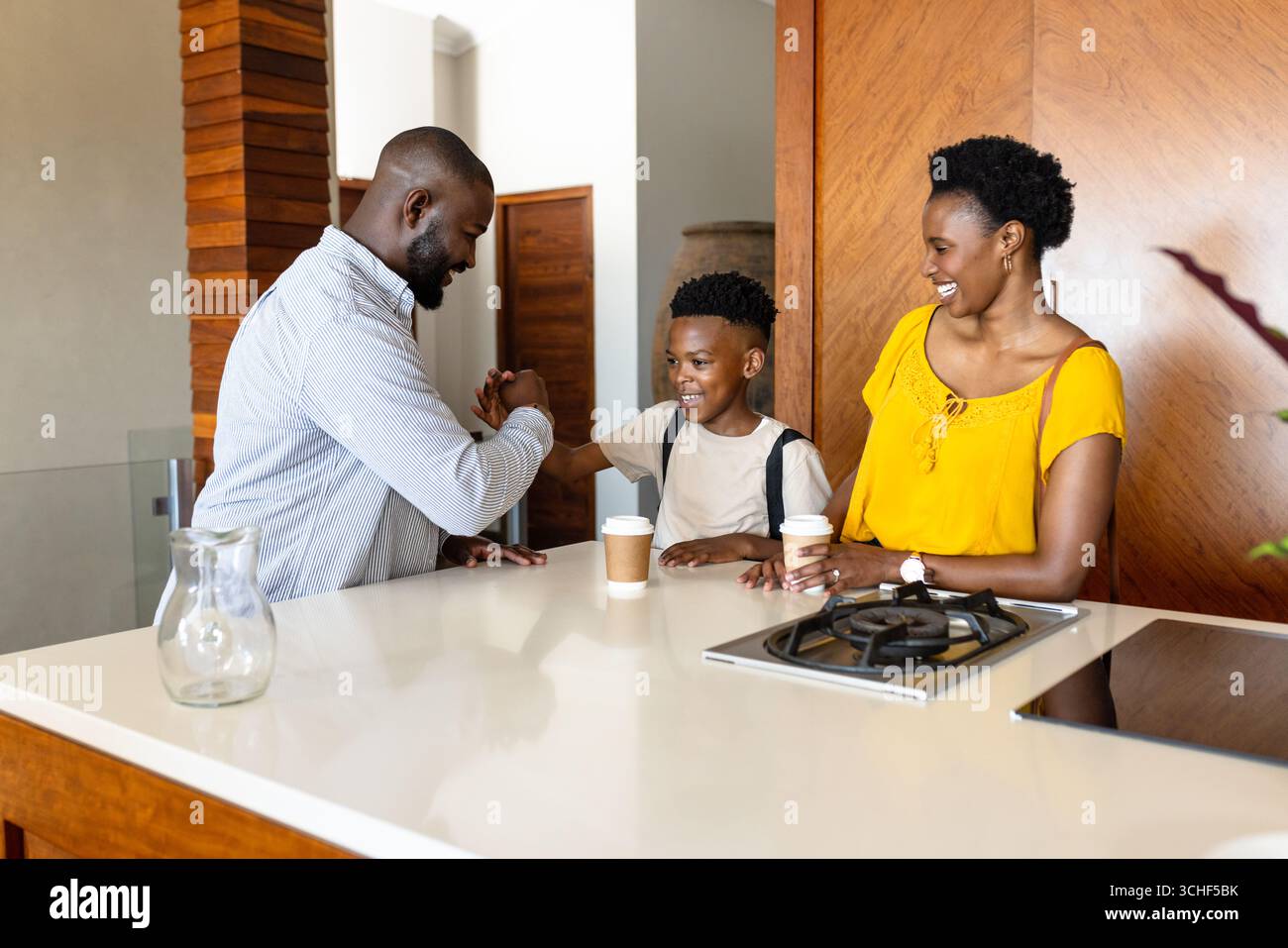 In modern kitchen, African American family having morning coffee ...