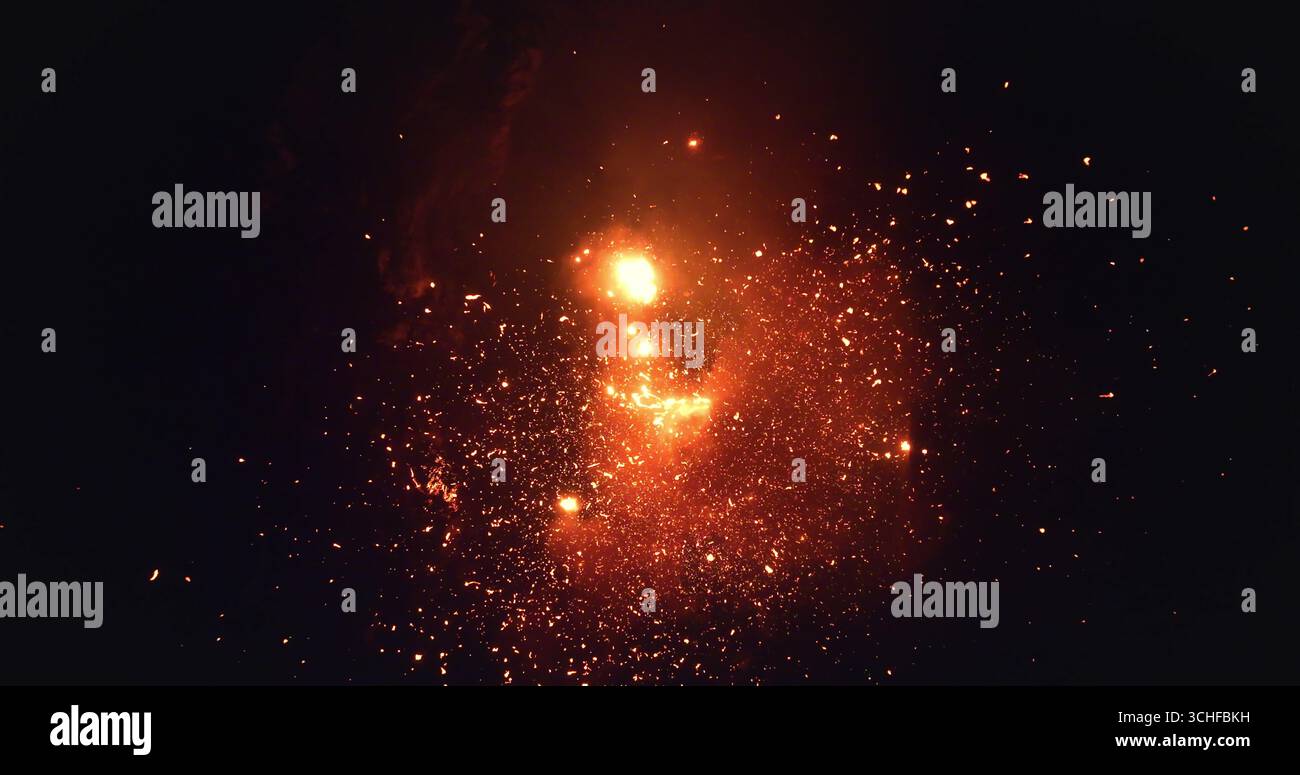 Aerial drone capturing a volcano erupting at night, showering the dark ...