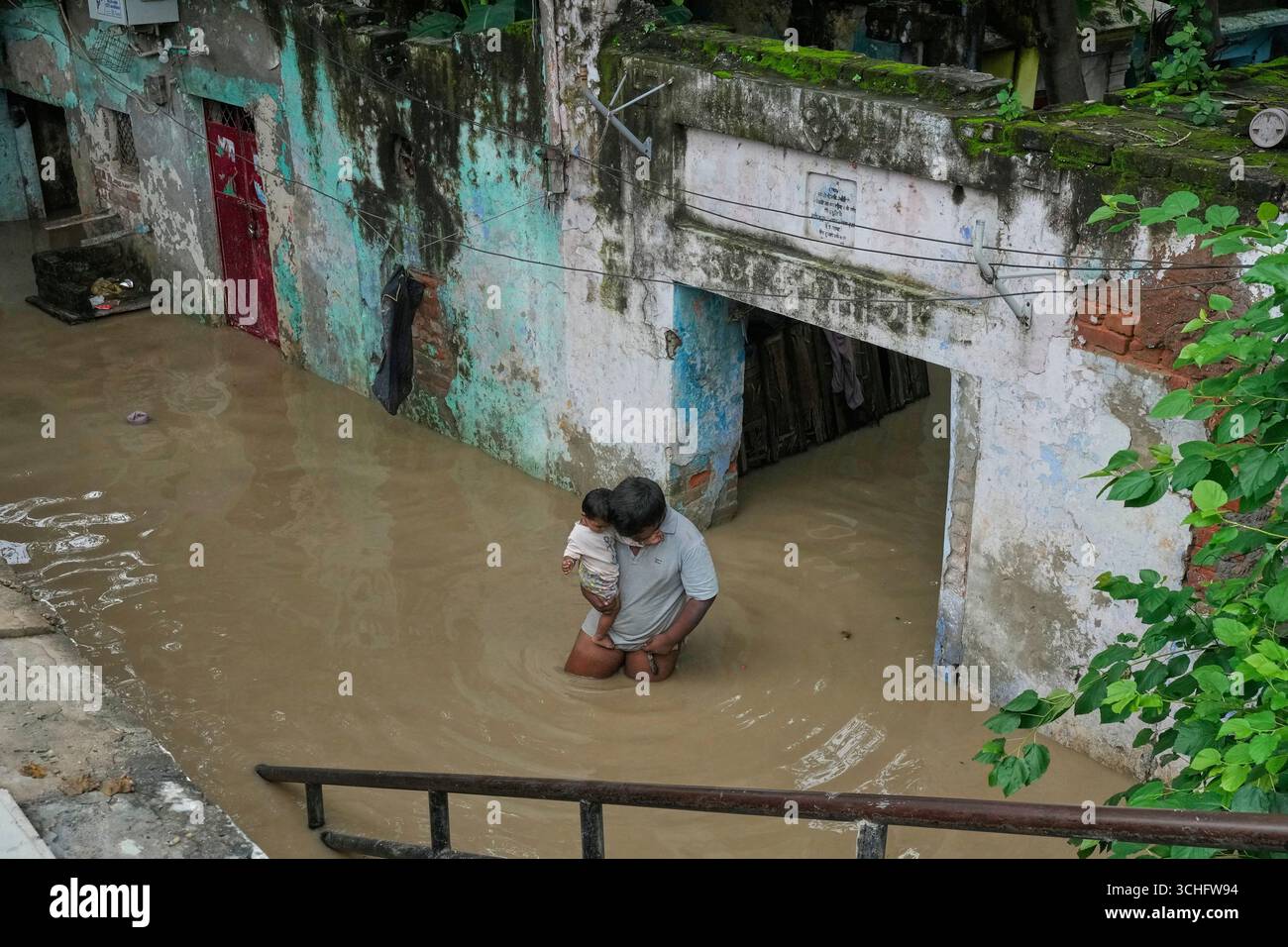 A resident carries his son and wades through floodwater after the river ...