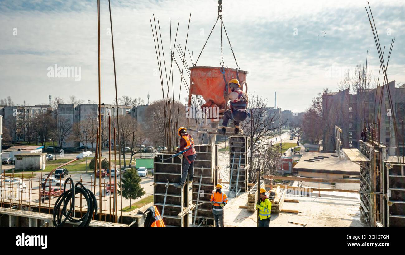 Above view on construction workers as unloading conical metal bucket ...