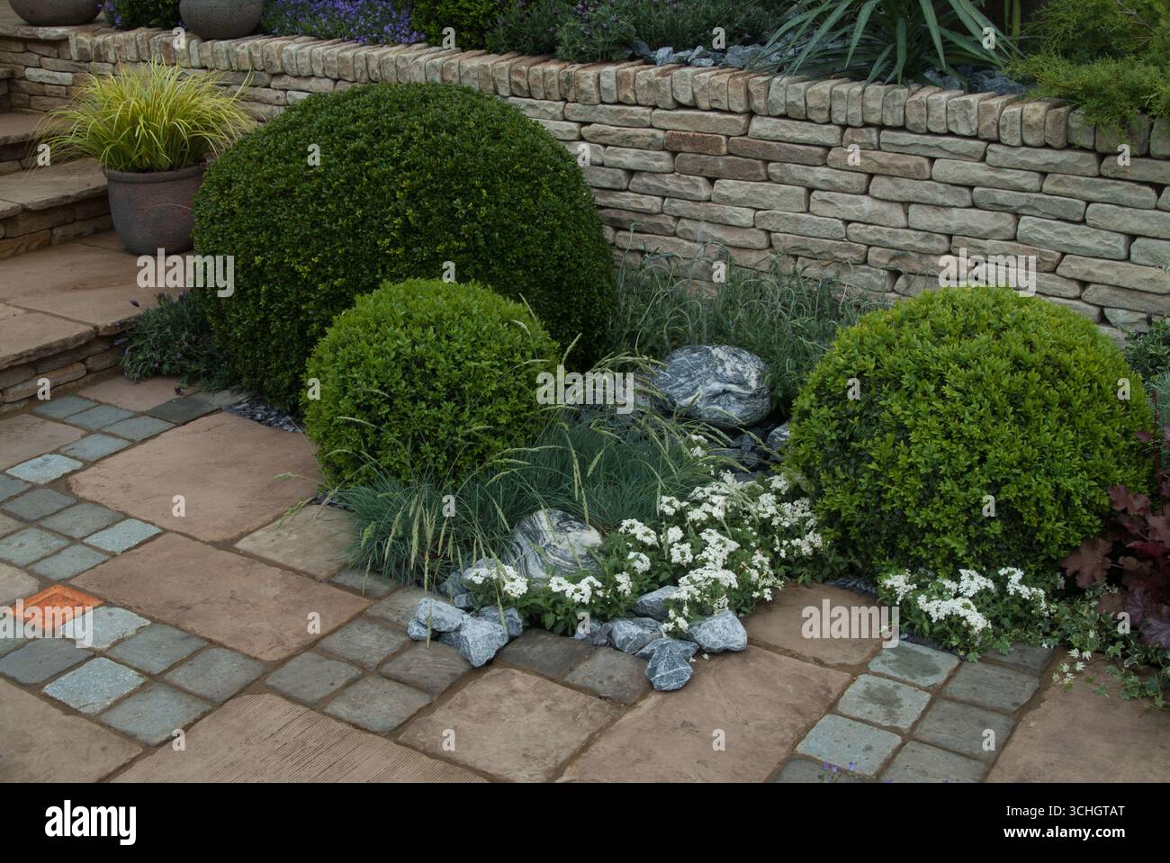 Rounded green shrubs complement stone pathways and decorative rocks in ...