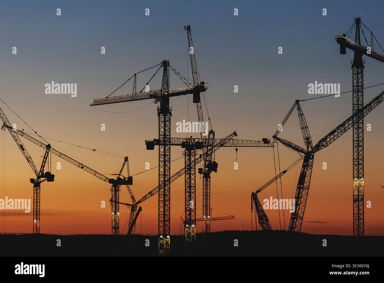 Kraene zeichnen sich ab im Abendlicht an der Baustelle der neuen ...