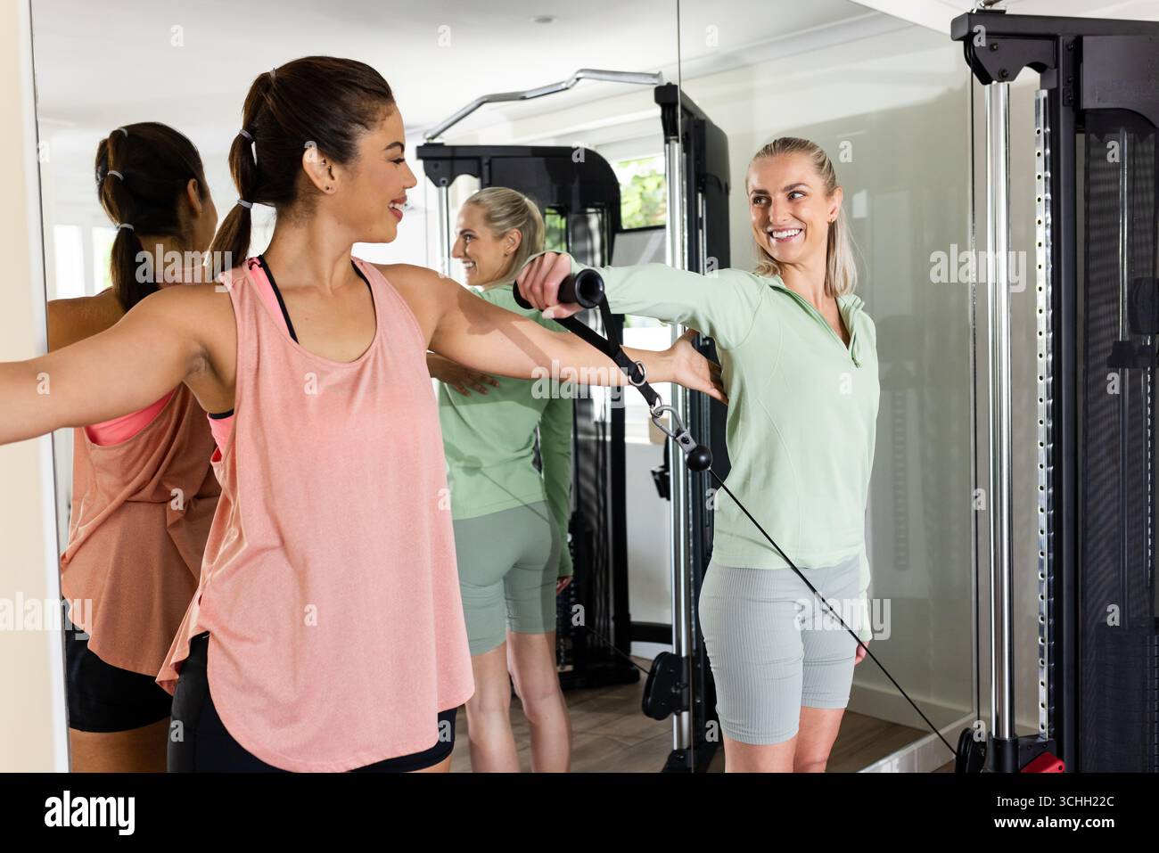 Exercising with cable machine, diverse female friends in gym supporting ...
