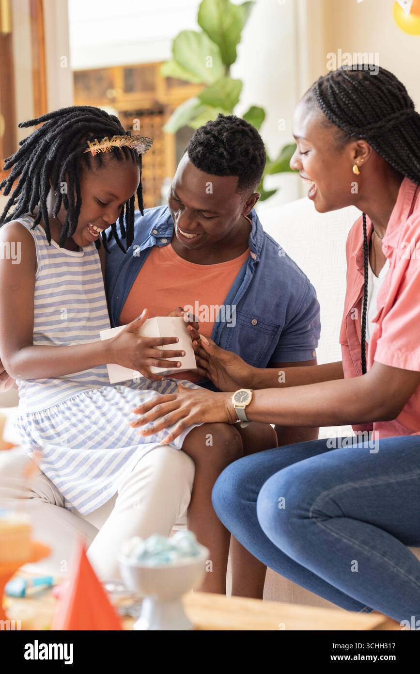 Family celebrating at home, daughter opening gift with parents, all ...